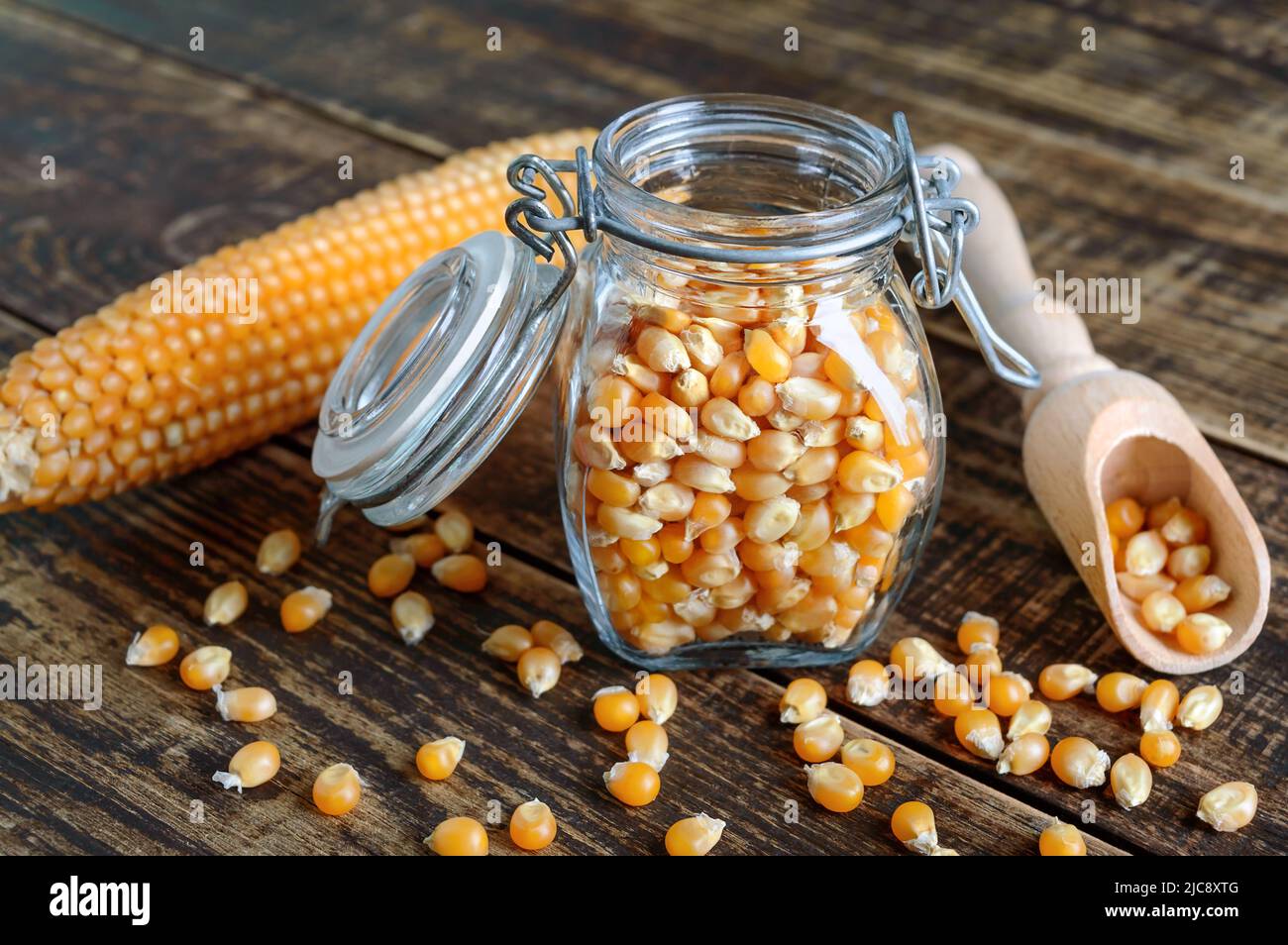Corn grains in a glass jar on a wooden background. Maize for popcorn ...