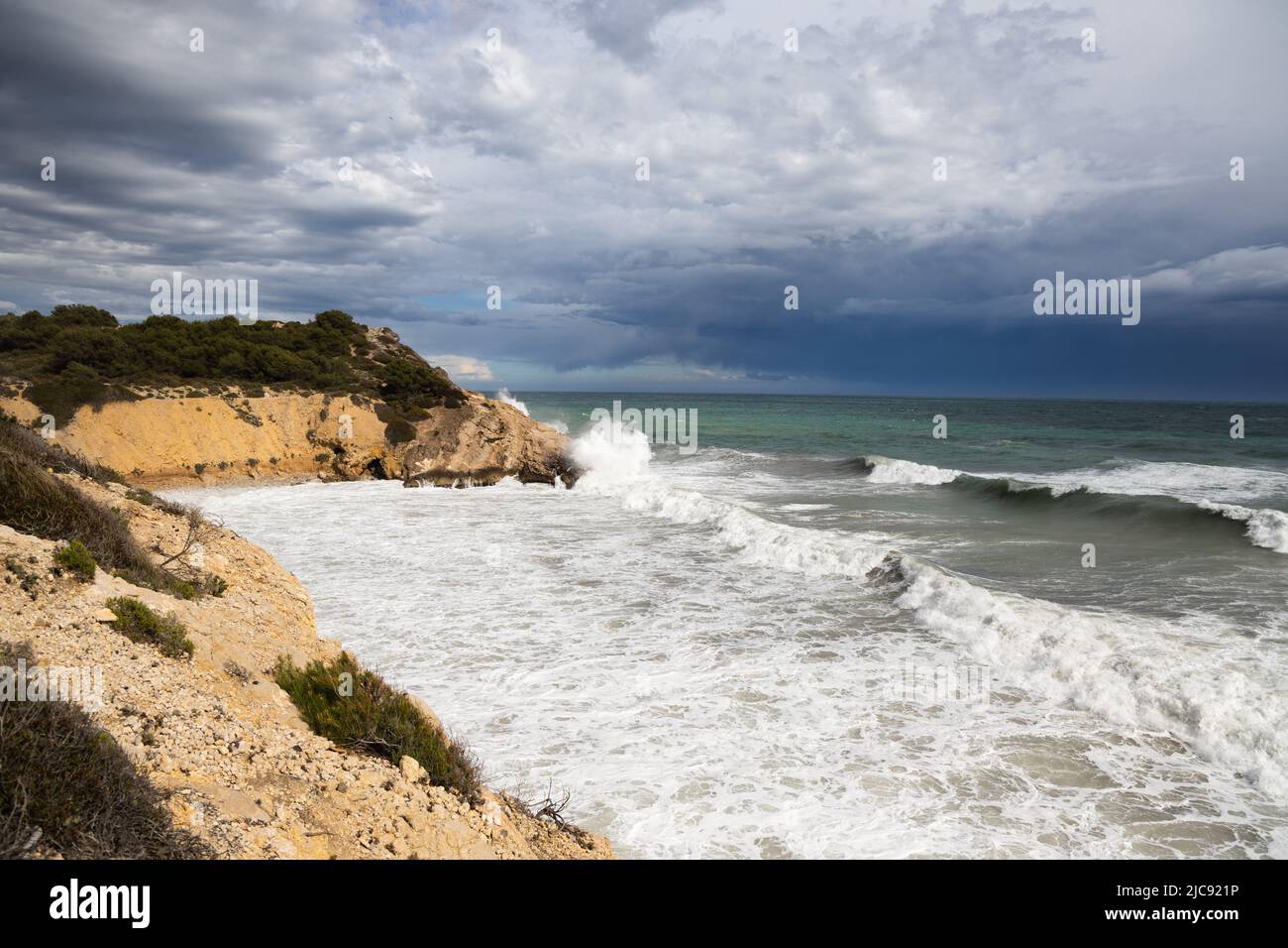 Stormy coastline with water splash and dark sky, sandy beach with ...