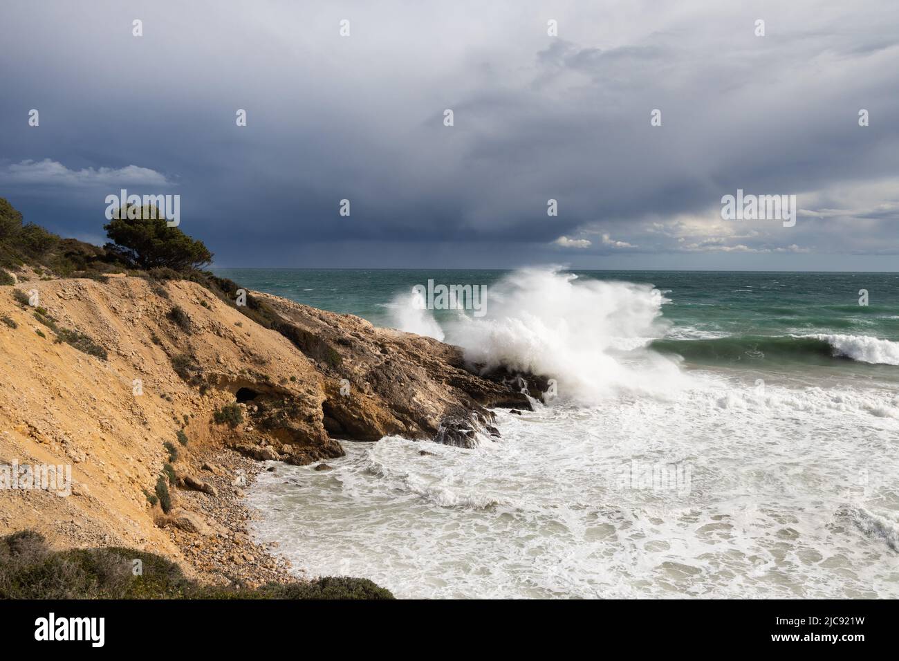 Stormy coastline with water splash and dark sky, sandy beach with ...