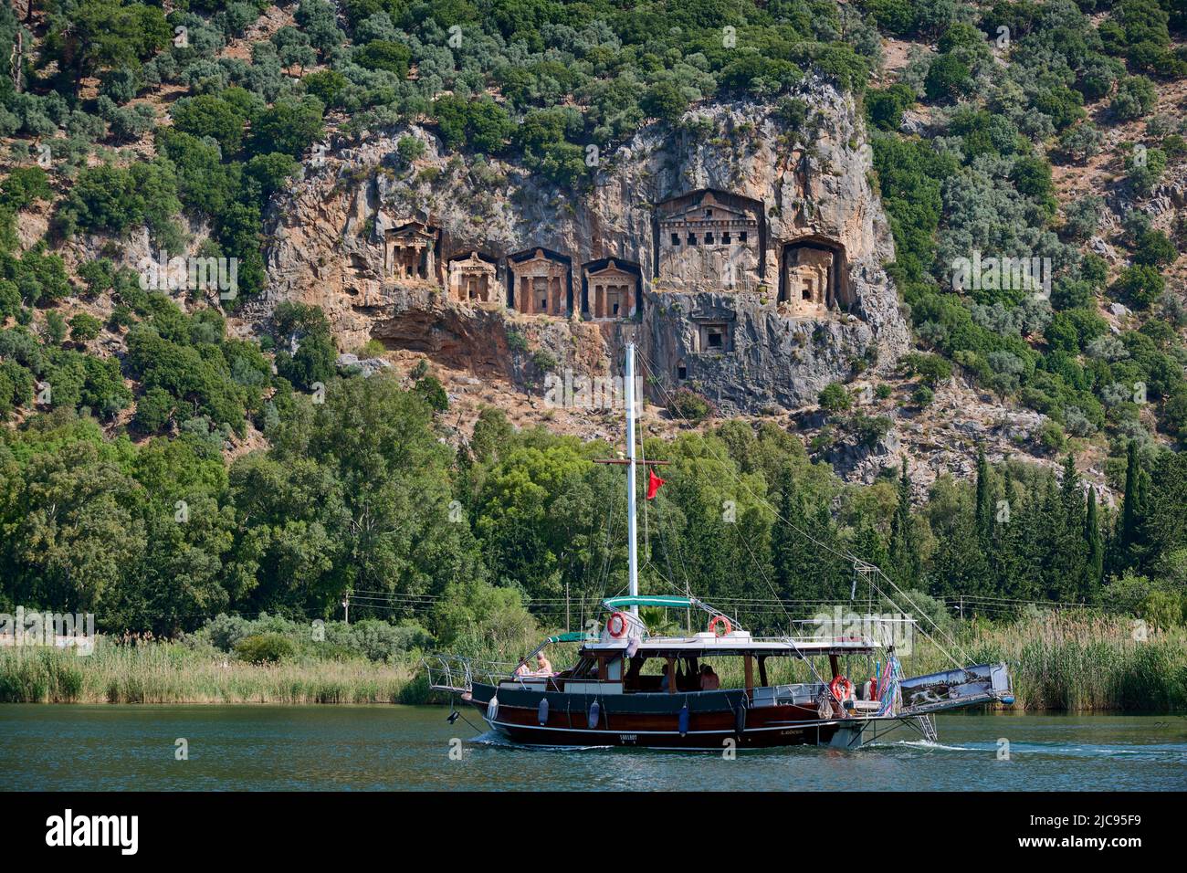Tourist ship in front of Lycian rock tombs in a rock face of Dalyan ...