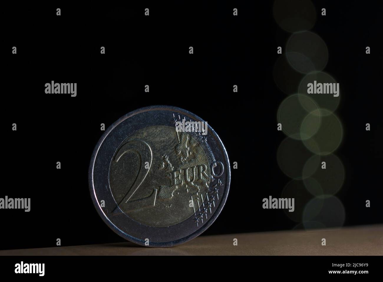 Close up macro shot of a 2 Euro coin front against bokeh lights, close ...