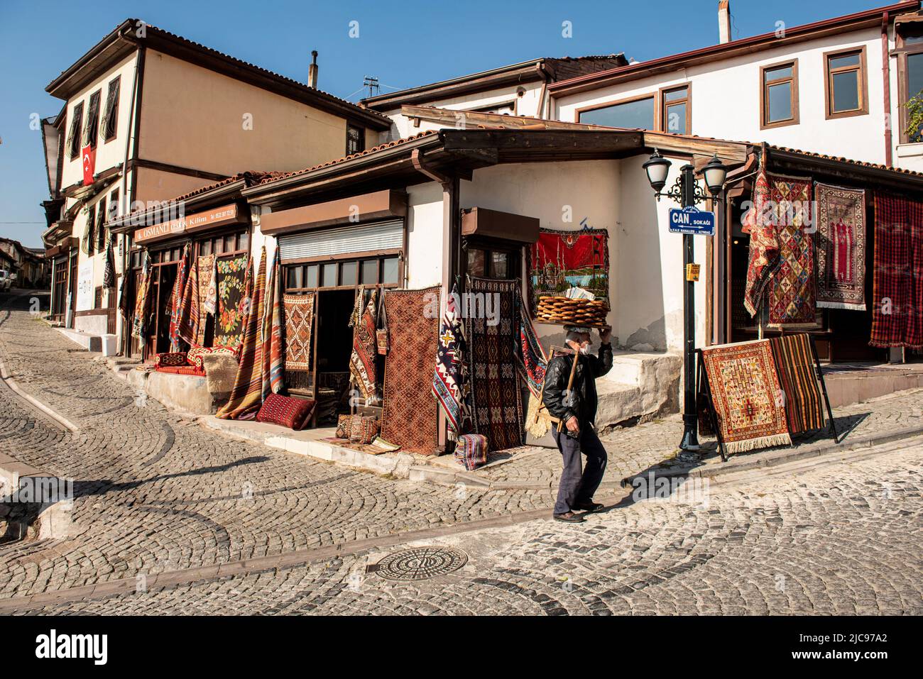 Traditional Turkish Simit seller walking past Antique carpet shops in ...