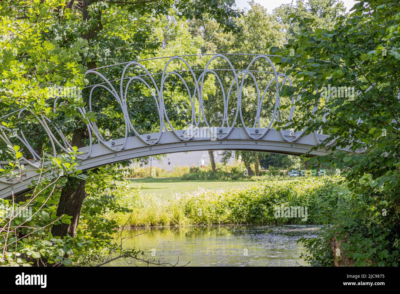 Gray metal bridge over a stream surrounded by lush green trees and wild ...