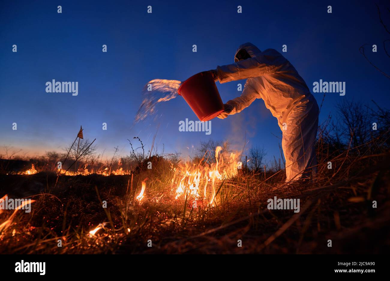Research scientist fighting fire in field with blue night sky on ...