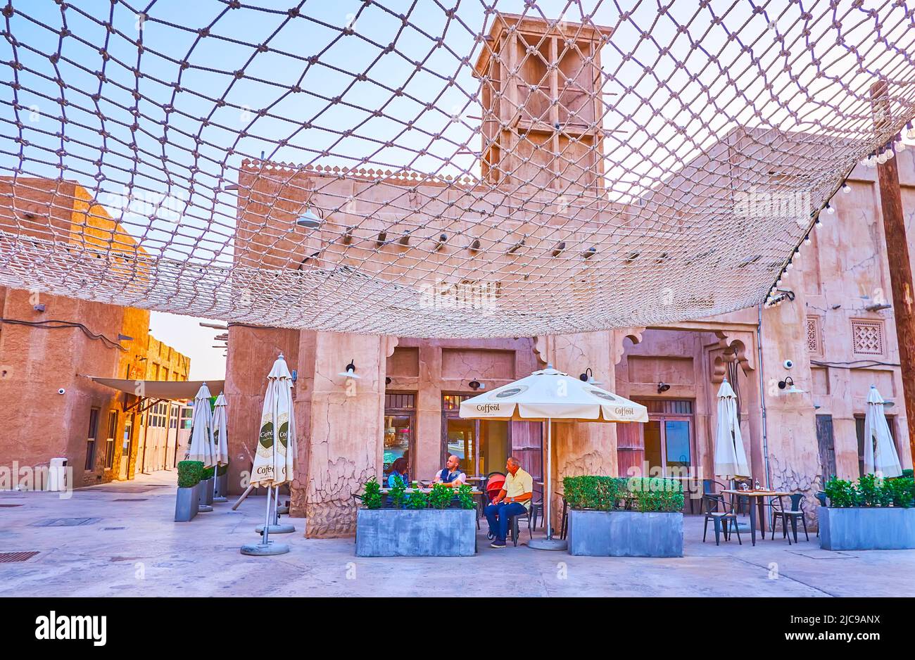 The evening street of Al Seef with fishinf net awning, tourist cafe in ...