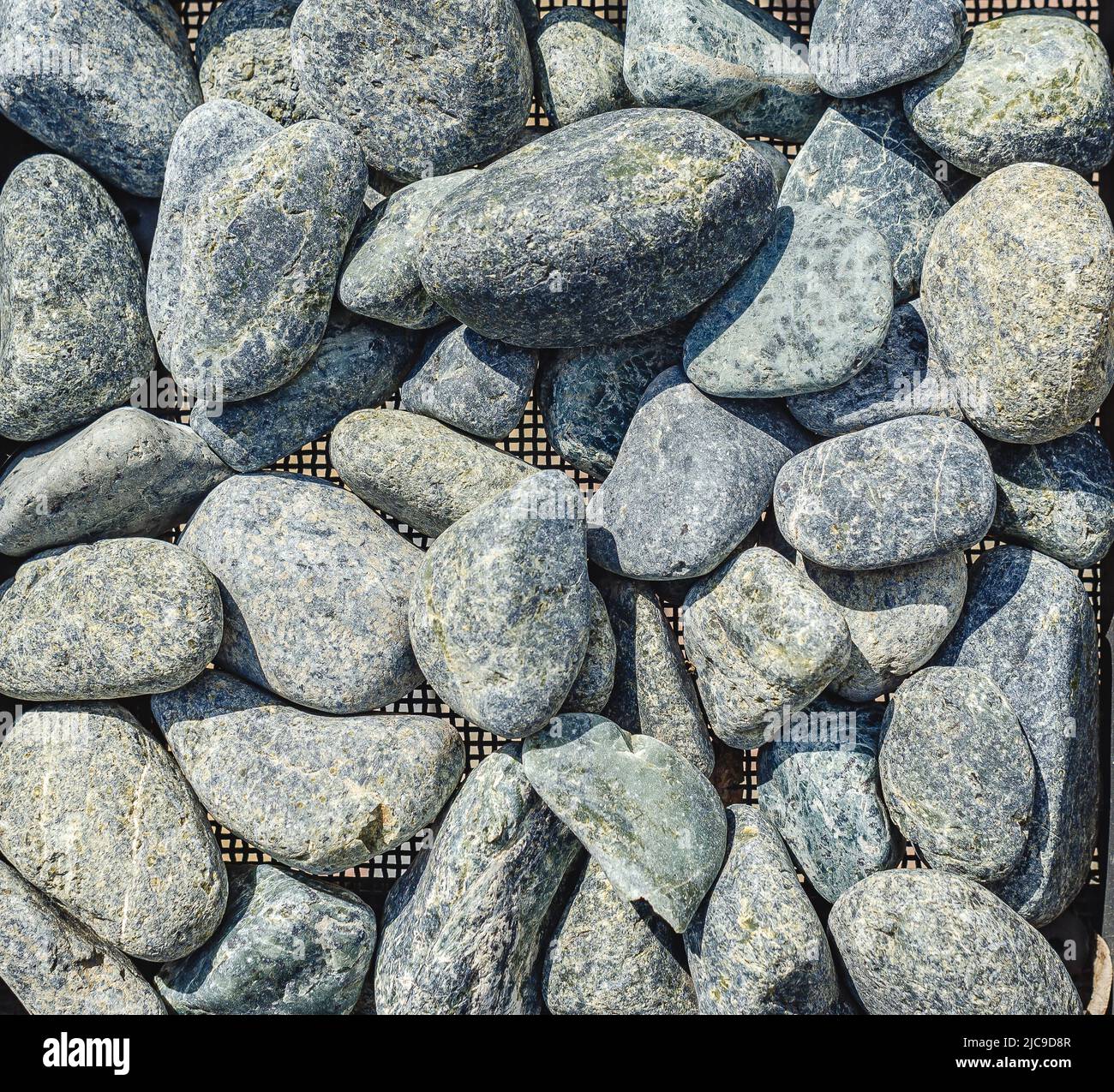 Round gray river stone. Lots of stones in construction sieve. Use of ...