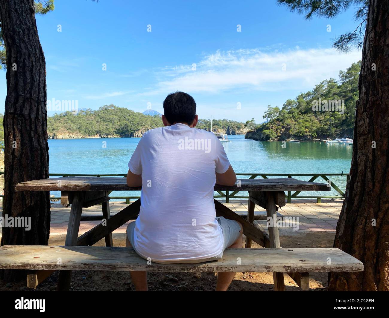 man sitting on bench watching sea or lake or bay view. at katranci bay ...