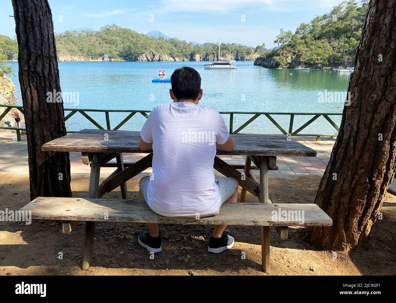 man sitting on bench watching sea or lake or bay view. at katranci bay ...