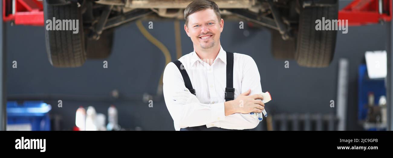 Qualified mechanic with car behind placed on lifter hoist in garage ...