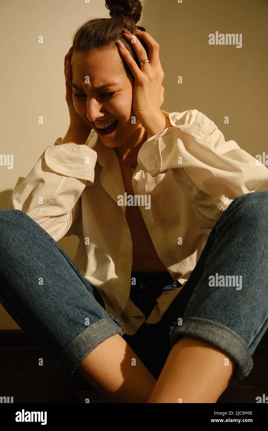 serious young woman feeling sad and scared, depressed. Sitting on white ...