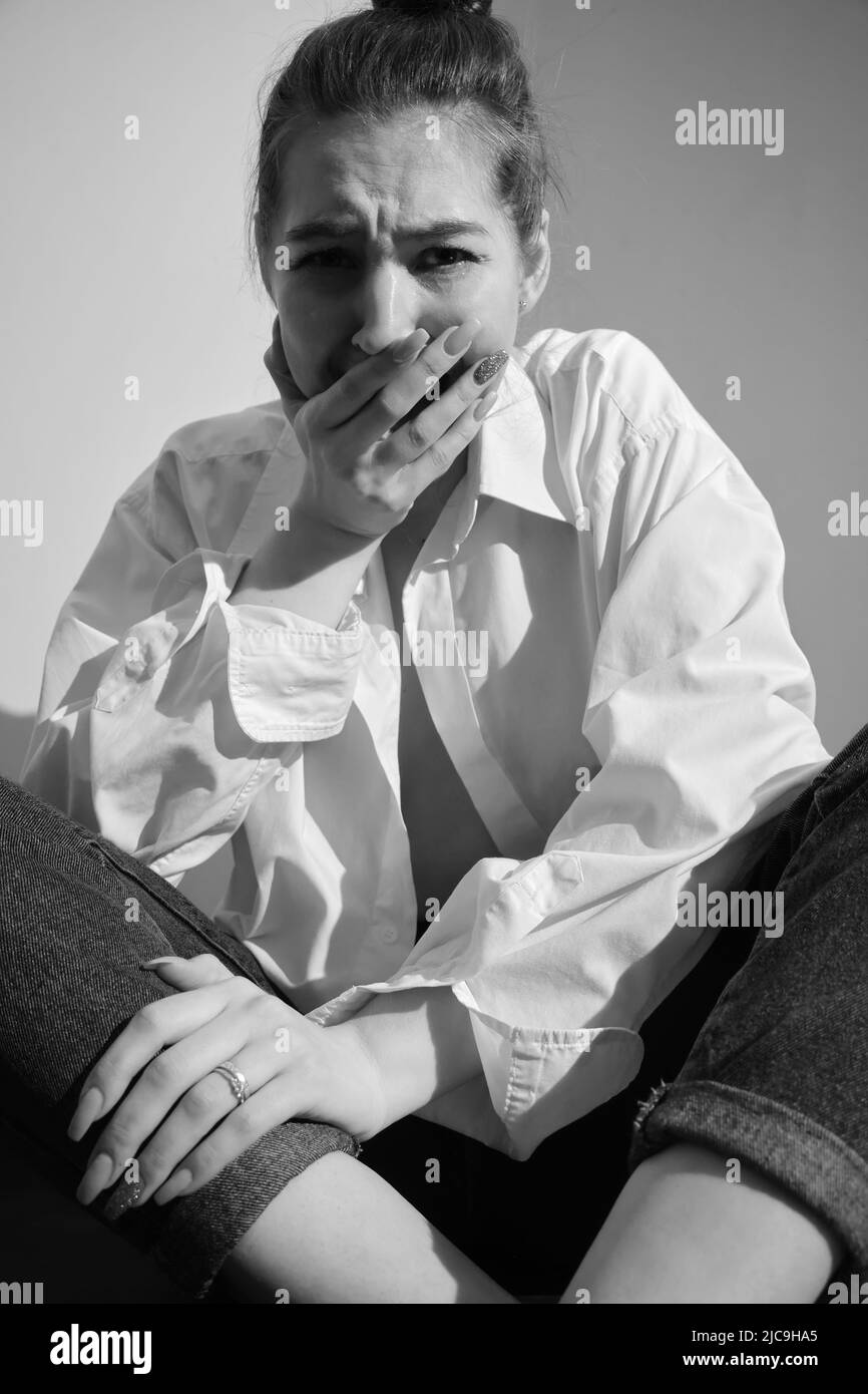 serious young woman feeling sad and scared, depressed. Sitting on white ...