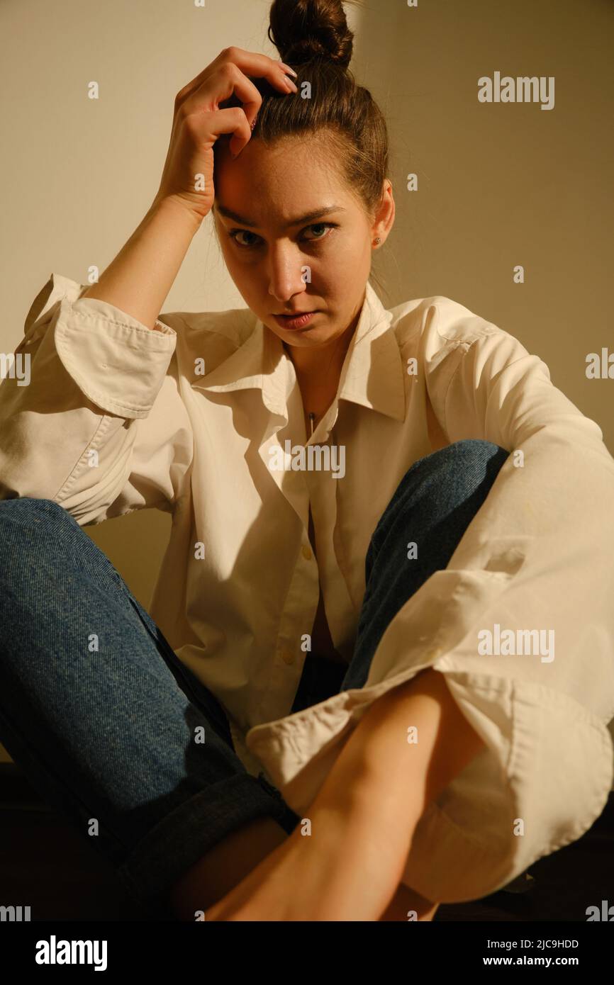 serious young woman feeling sad and scared, depressed. Sitting on white ...