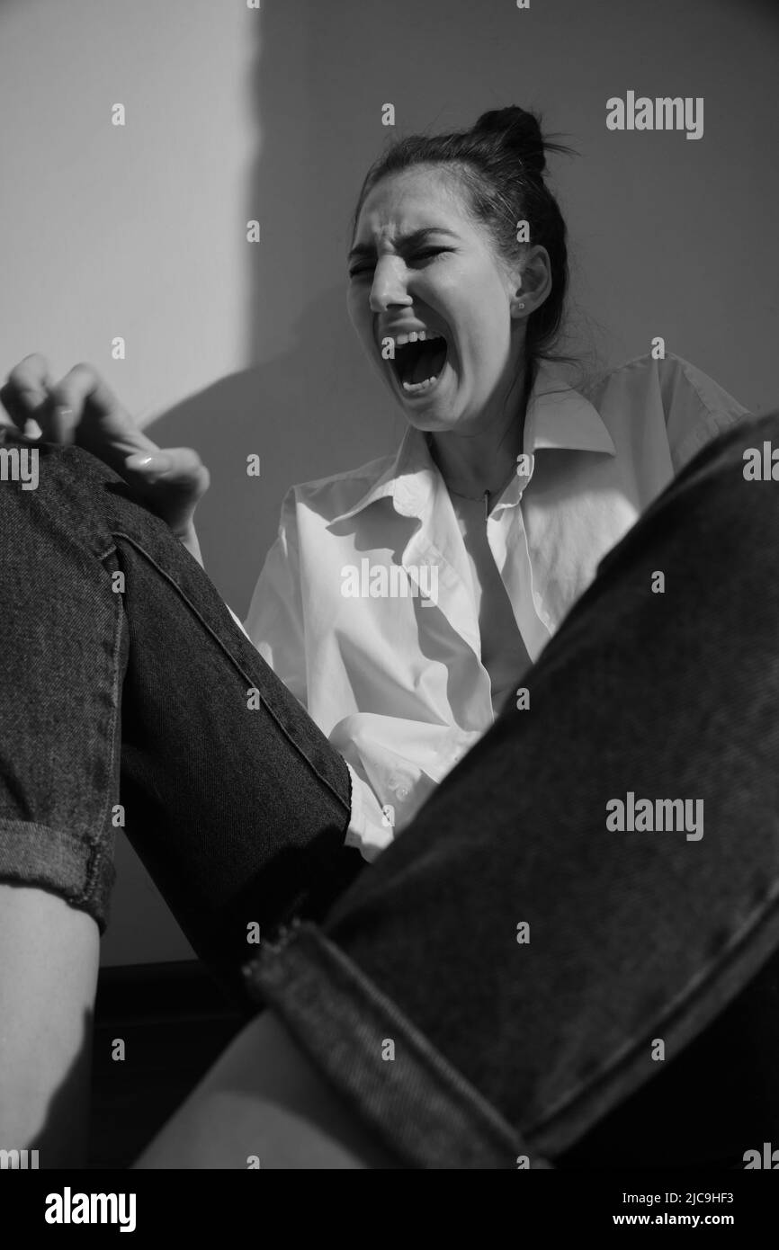 serious young woman feeling sad and scared, depressed. Sitting on white ...