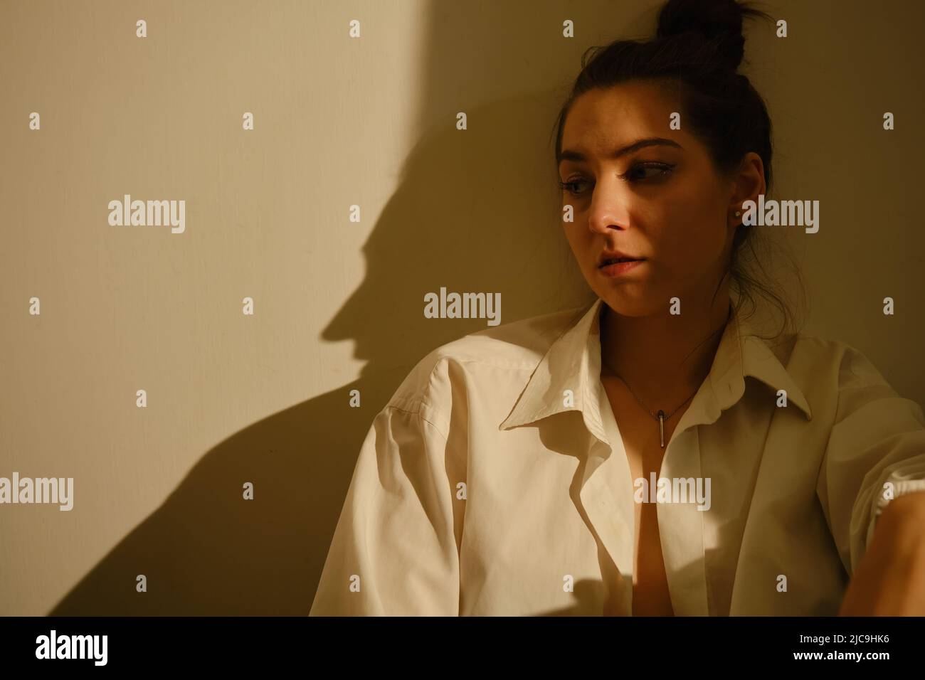 serious young woman feeling sad and scared, depressed. Sitting on white ...