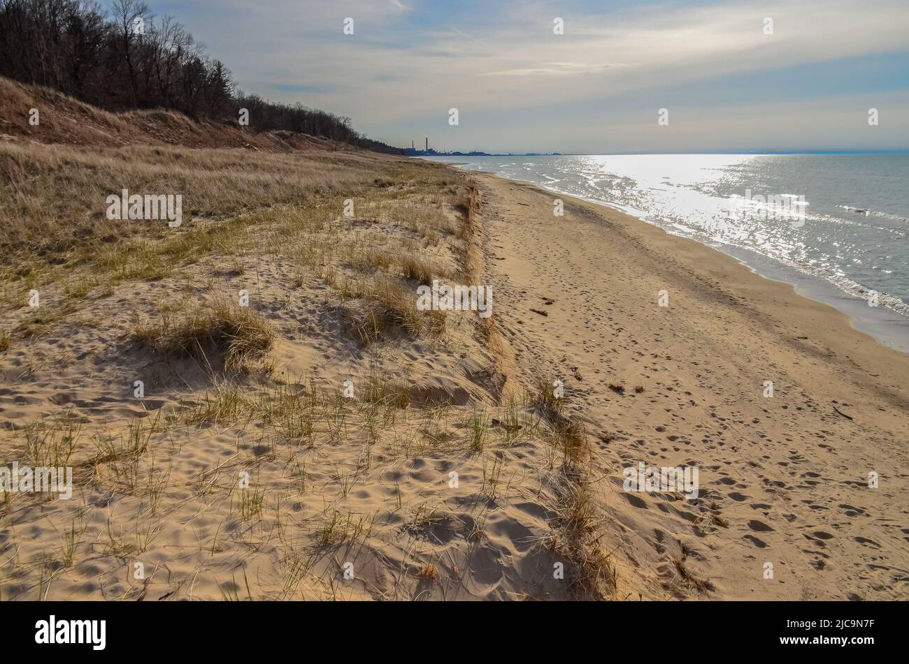 Sand dunes on the shore of a large lake, reflection of the sun in the ...
