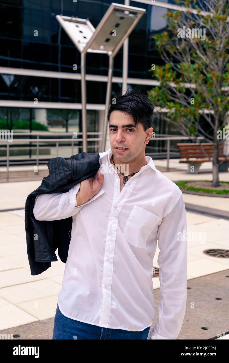 Young man holding his jacket with his hand on his shoulder with a ...