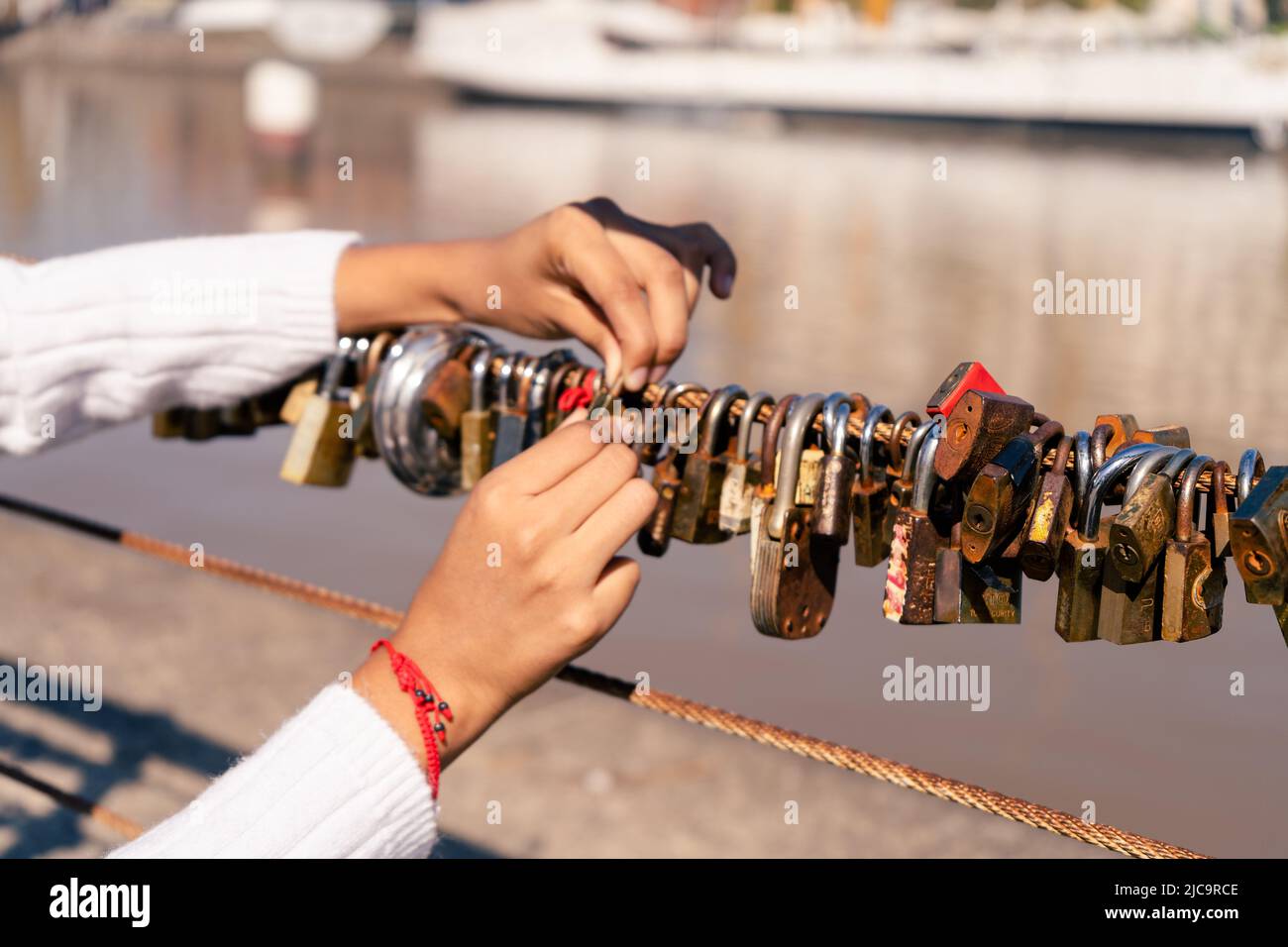 Woman's hands putting a padlock on one of the bridges in a city ...