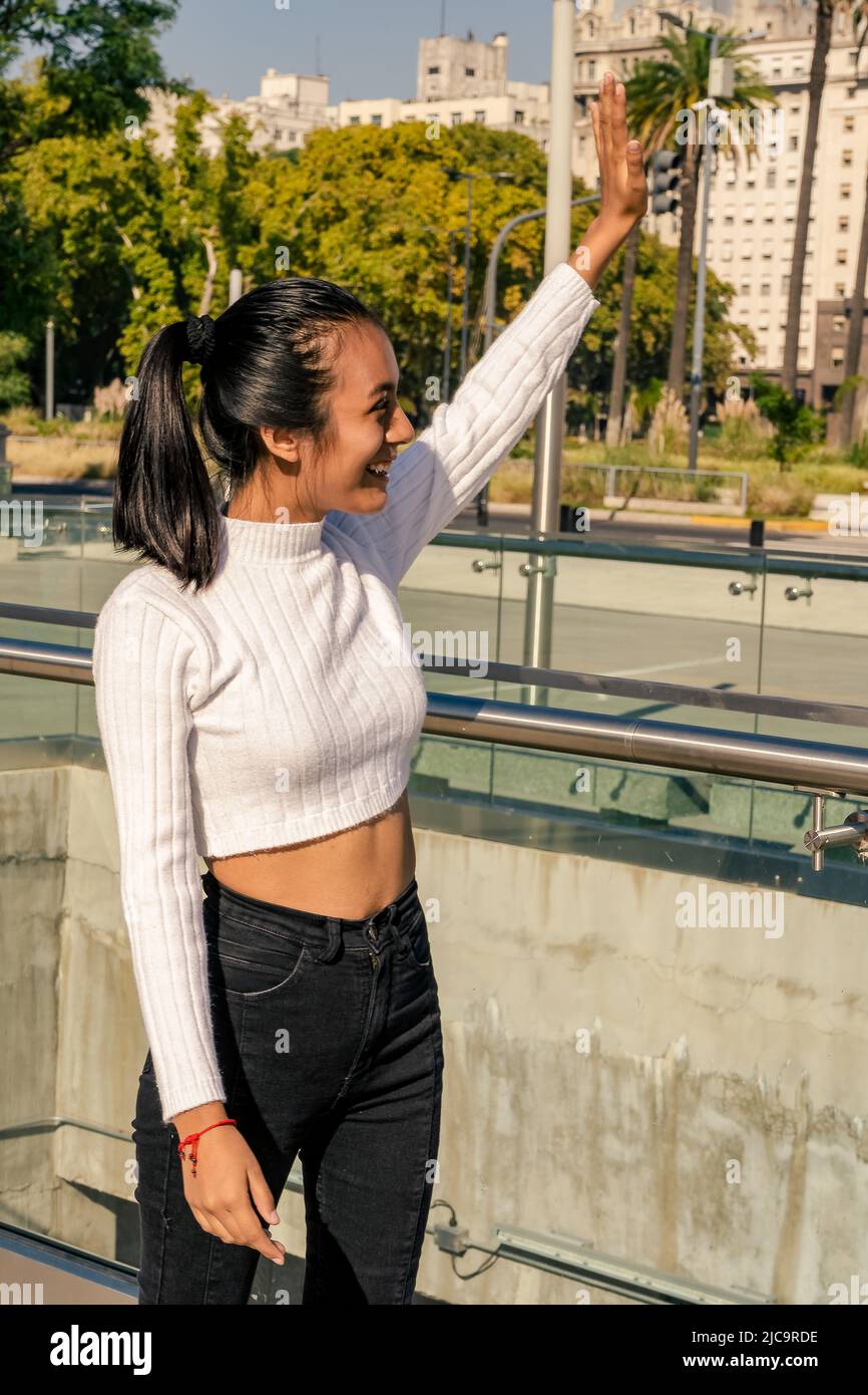 Beautiful young Latin American woman smiling and waving her hand ...