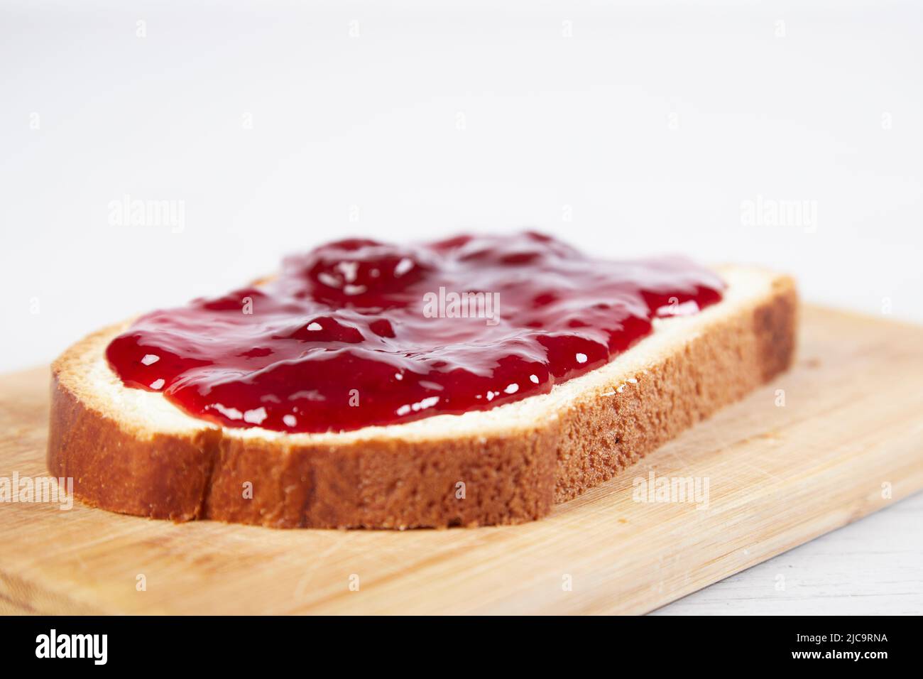 a piece of white bread with strawberry jam Stock Photo - Alamy