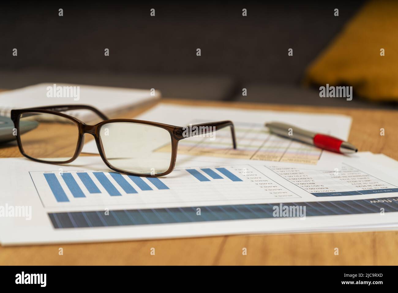Work table at home with pen, papers, bills, charts, glasses, computer ...