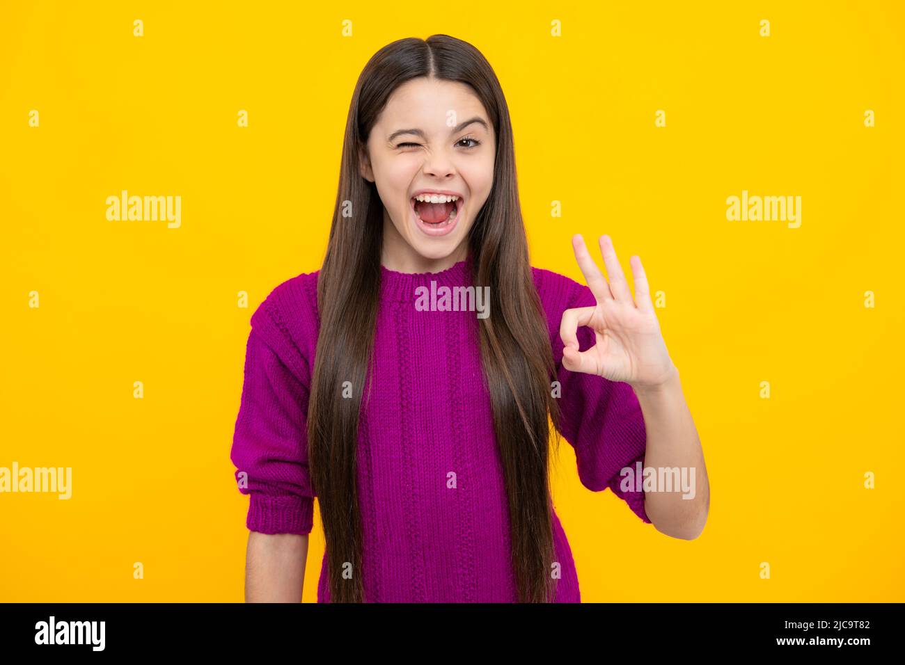 Okay. Beautiful child girl making ok sign and winking on yellow ...