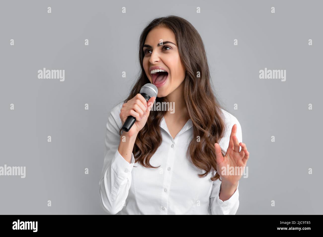 Young excited woman singing a song with a microphone, presenting an ...