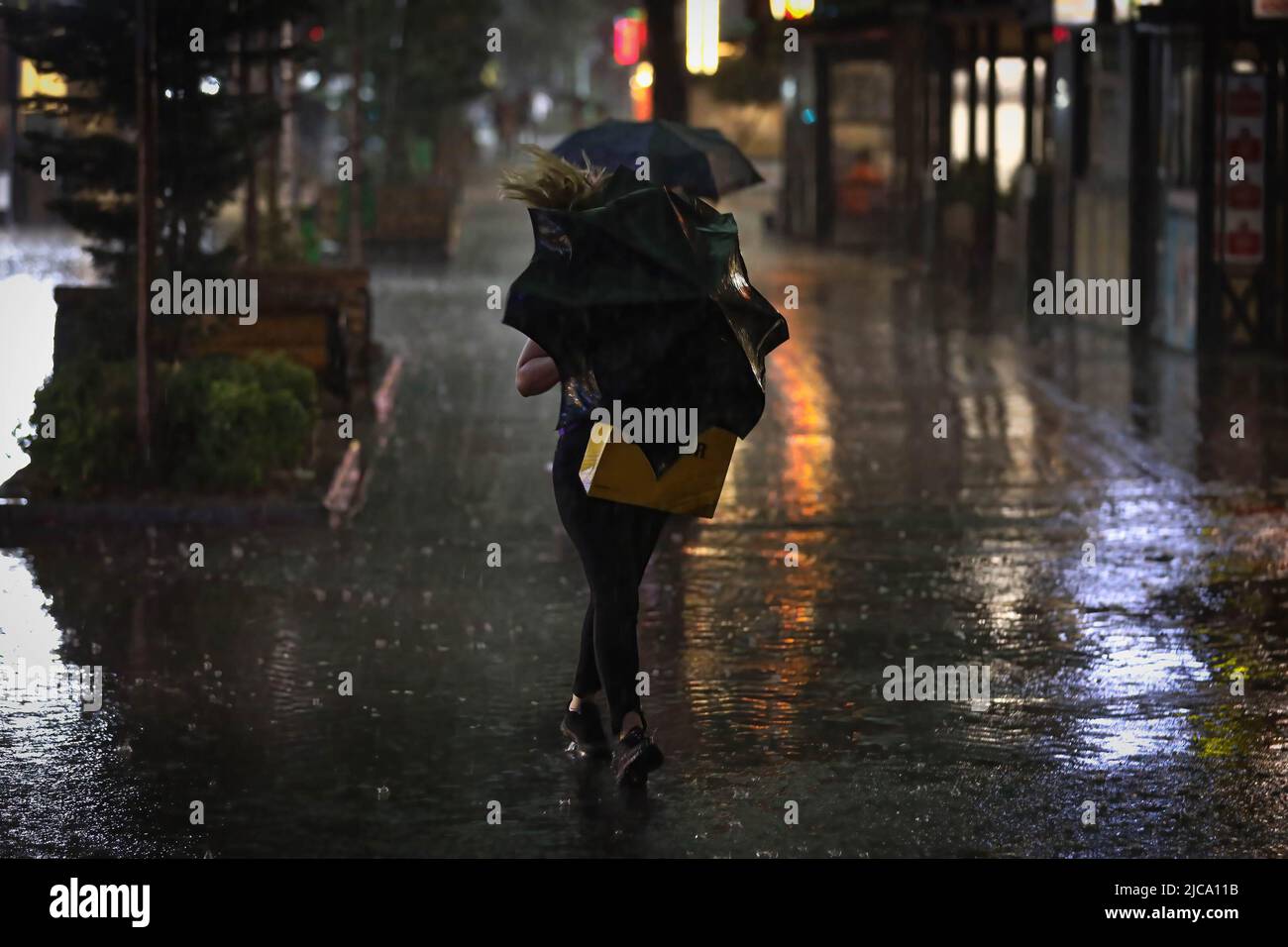 Ankara, Turkey. 11th June, 2022. A woman shelters under an umbrella ...