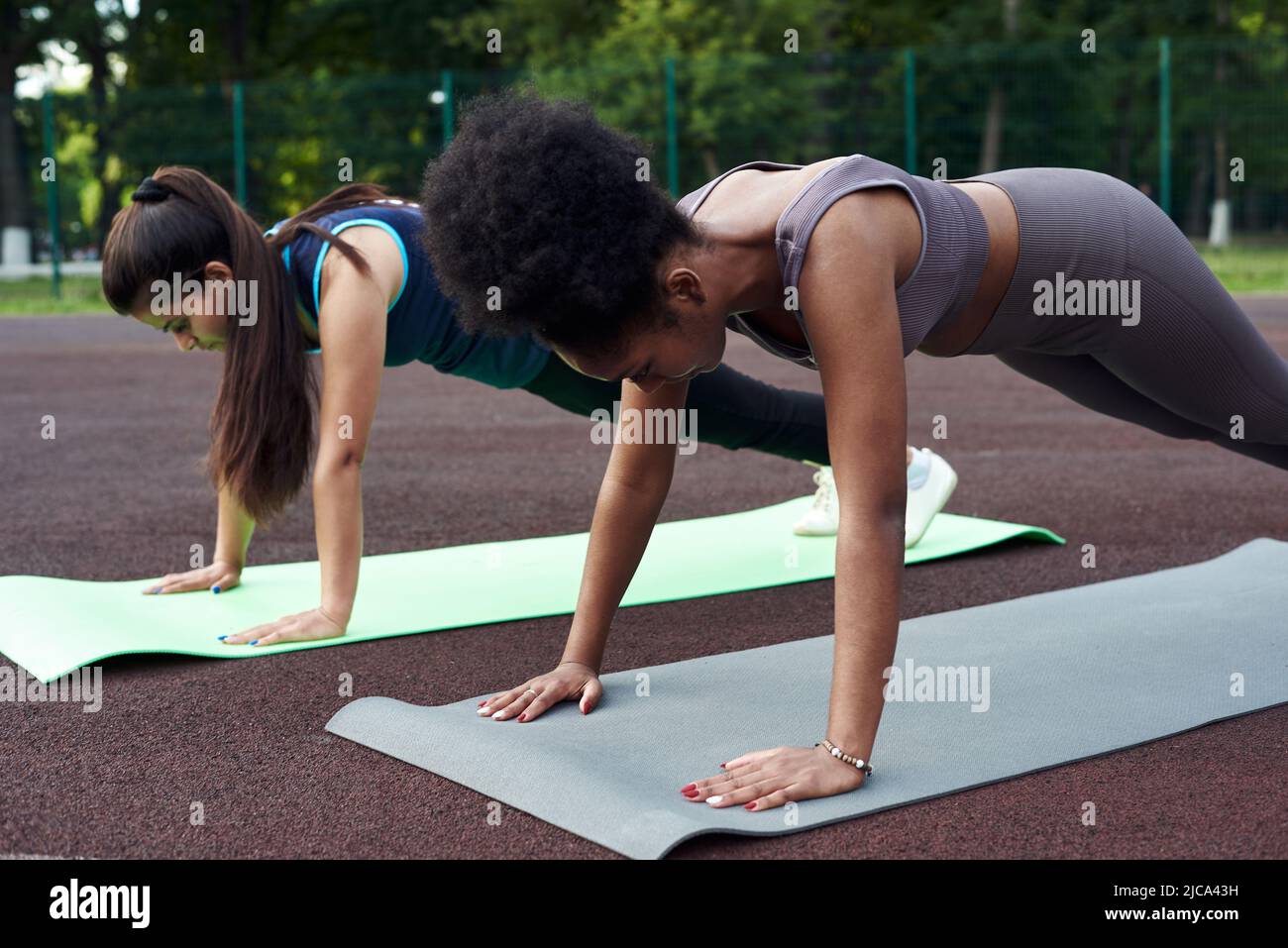 Two fitness women of different nationalities in a plank position in an ...