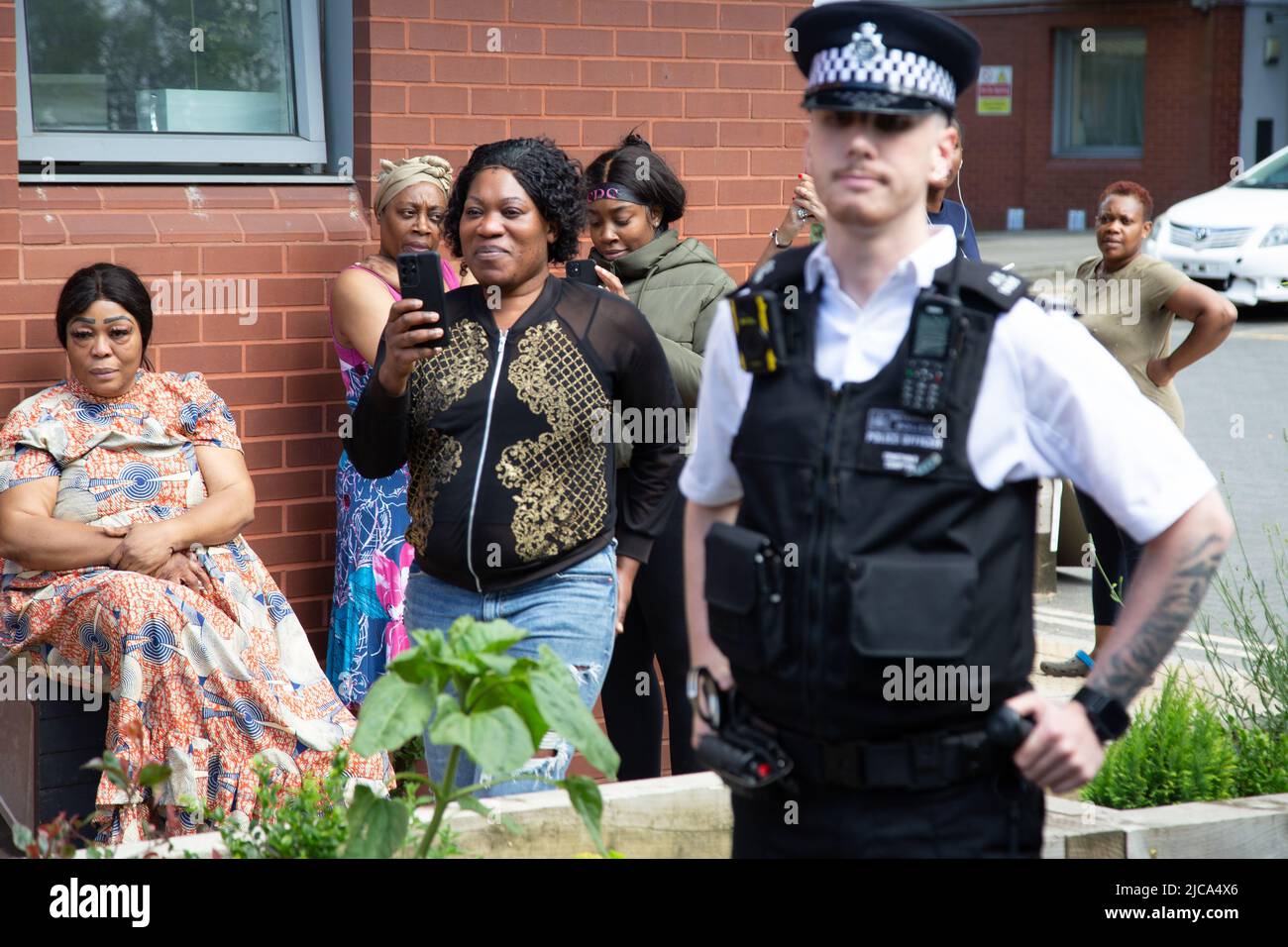 London, UK. 11th June 2022. Residents of a housing estate look during ...