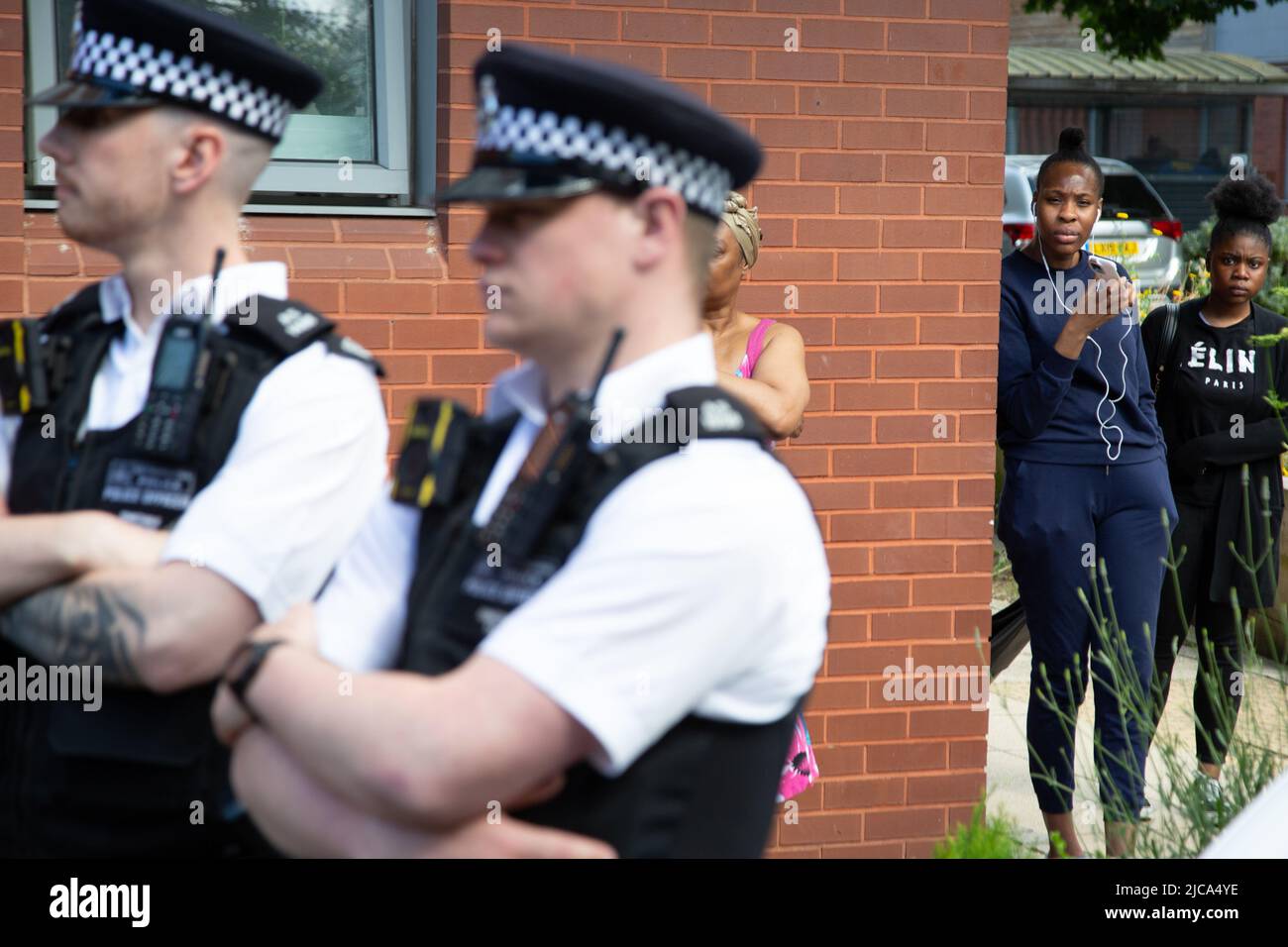 London, UK. 11th June 2022. Residents of a housing estate look during ...