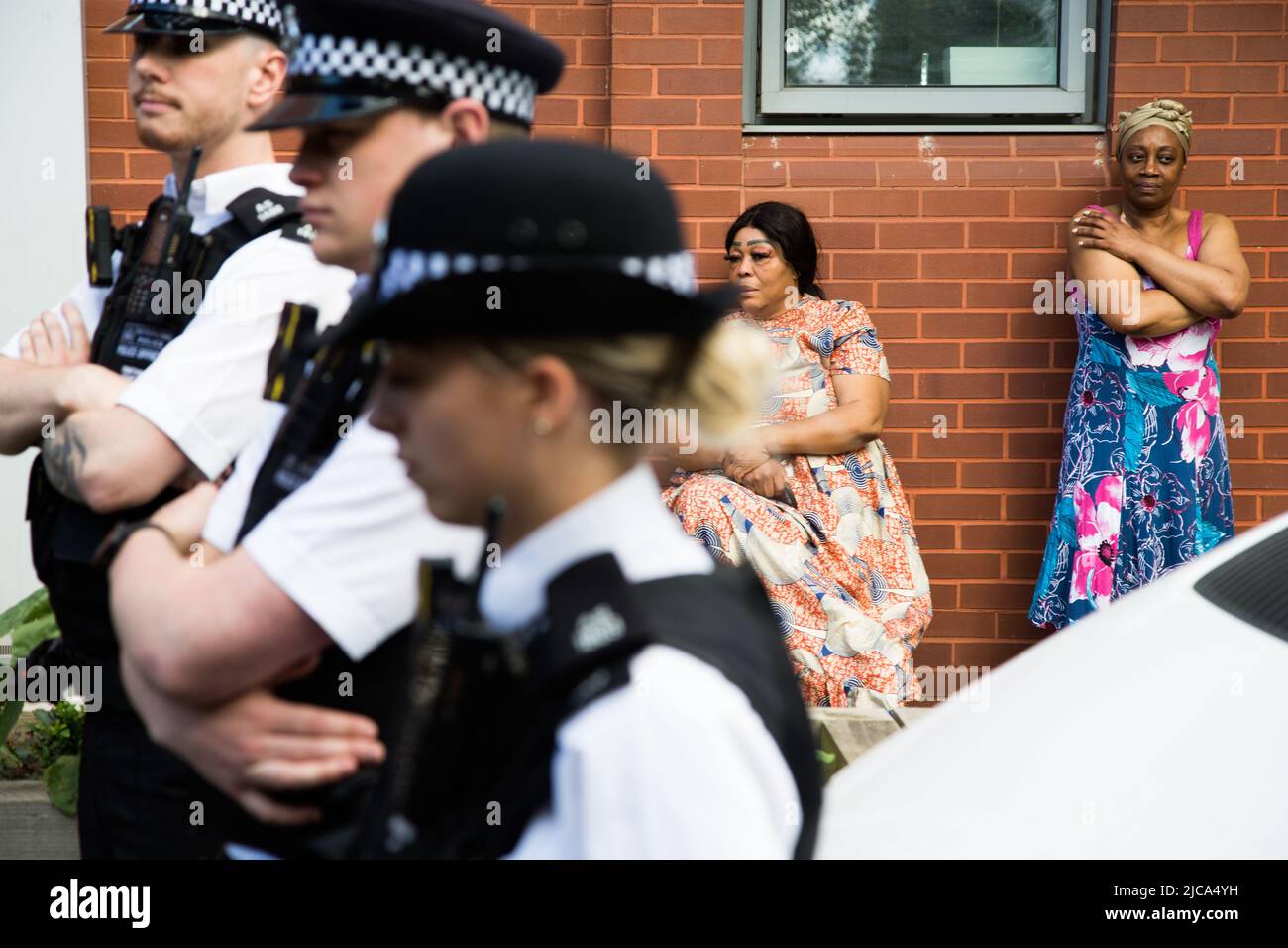 London, UK. 11th June 2022. Residents of a housing estate look during ...
