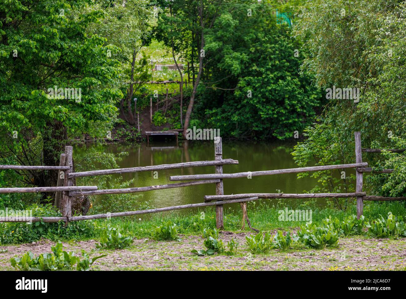 rustic log fence in front of pond or river with small pier Stock Photo ...