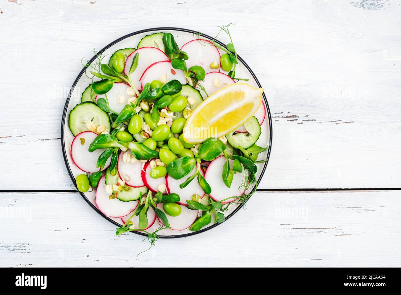 Fresh vegan salad with radish, cucumber, green pea, sunflower and soy ...