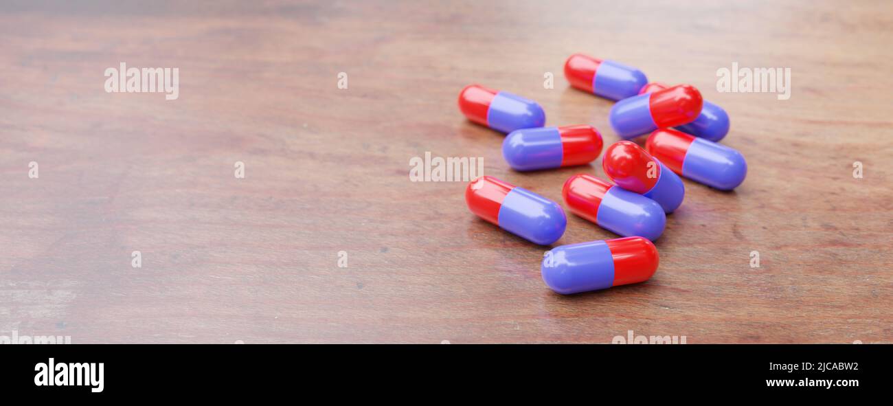 Medicine capsule, pill blue and red color on wooden background. Drug ...