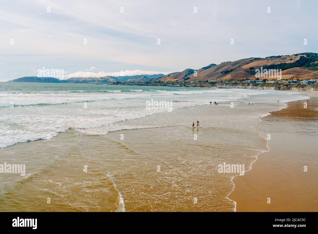 Wide sandy beach, green hills, and cloudy sky, California landscape ...