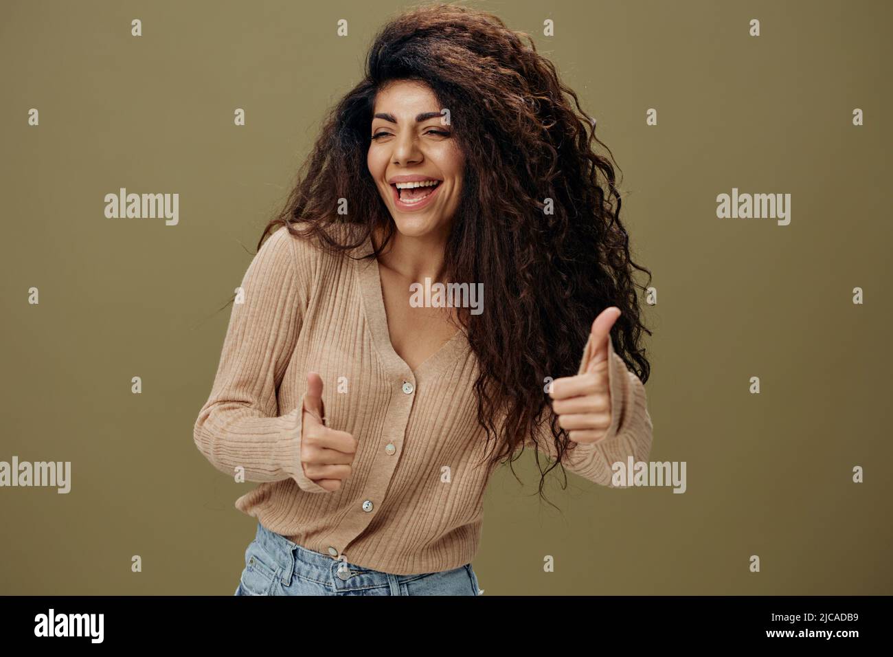 Happy enjoyed tanned curly Latin female in casual things show gesture ...