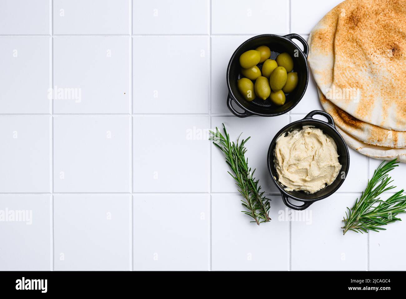 Hummus and pita bread set, on white ceramic squared tile table ...