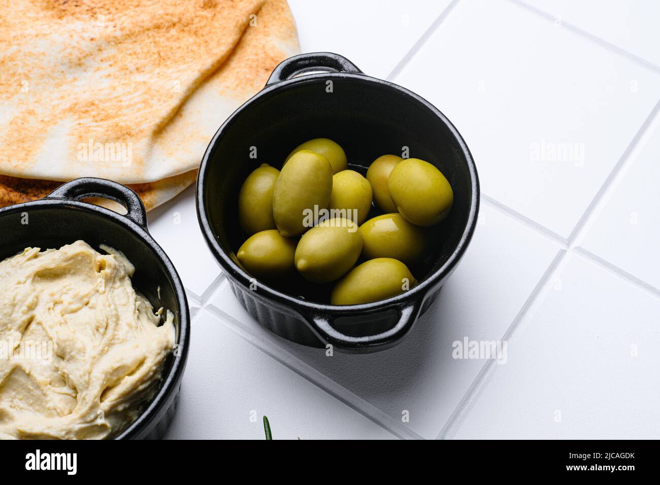 Greek green olives, on white ceramic squared tile table background ...