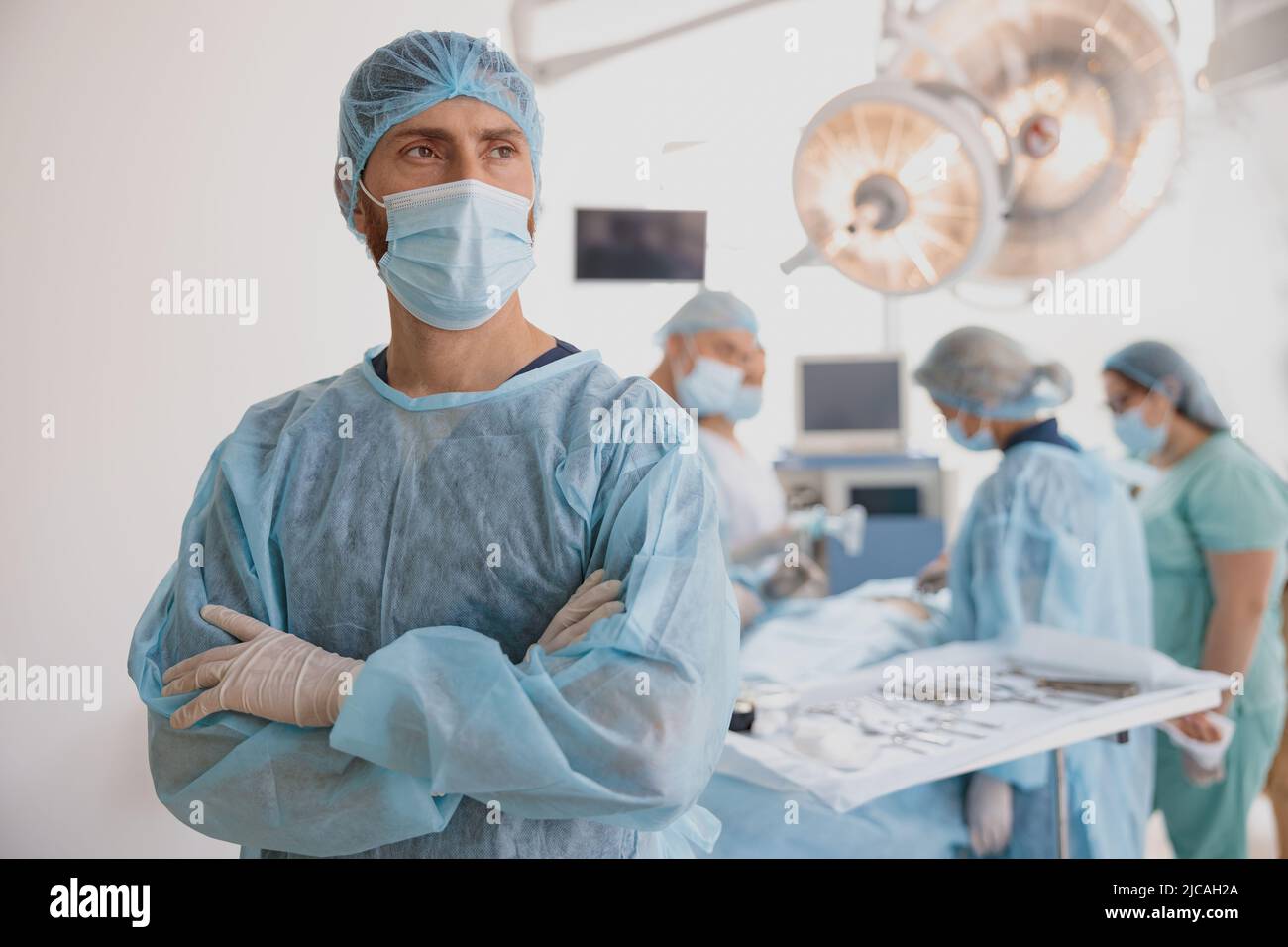 Surgeon in mask and gloves standing in operating room with crossing ...