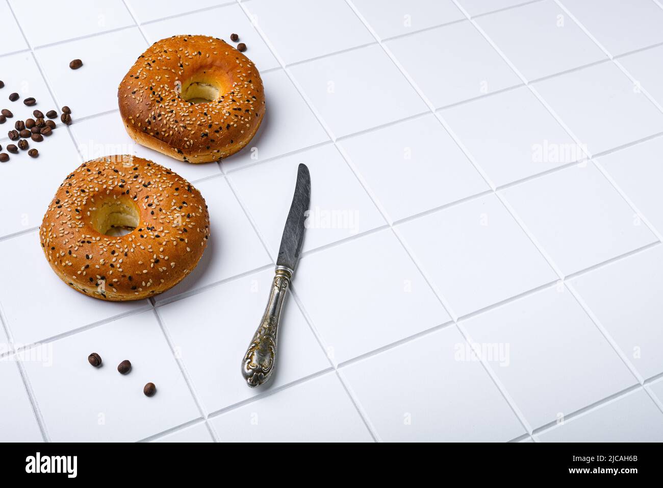 Fresh Bagels with Sesame set, on white ceramic squared tile table ...