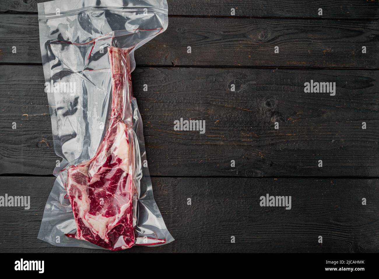 Dry aged raw tomahawk beef steak in plastic airtight pack, on black ...