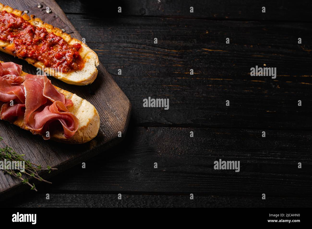 Traditional Spanish Jamon Serrano ham, on black wooden table background ...