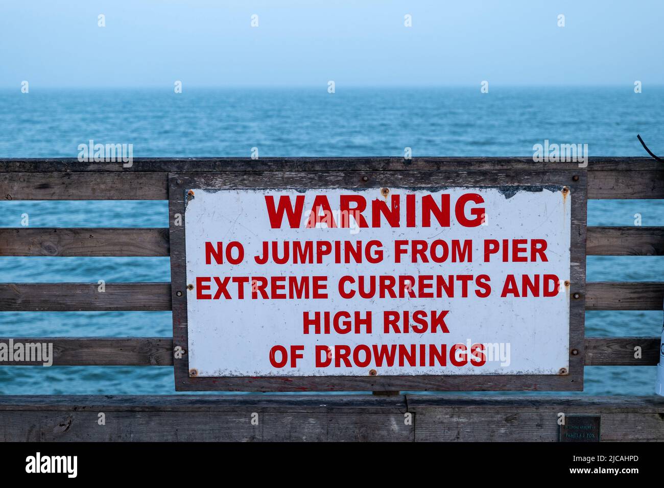 Sign on pier at the ocean. WARNING NO JUMPING FROM PIER EXTREME ...