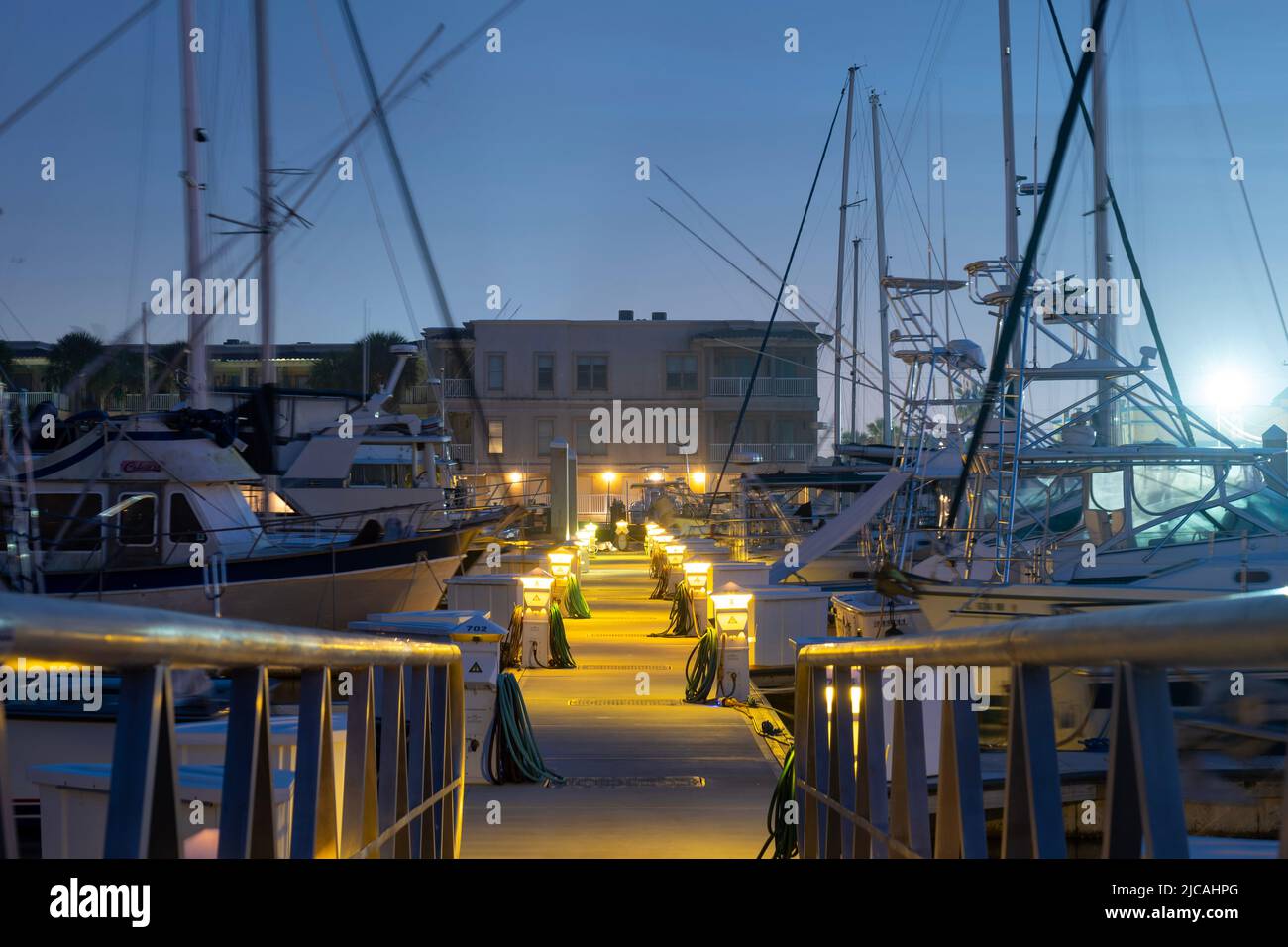 Marina dock and fishing boats with tall masts, on a foggy, hazy night ...