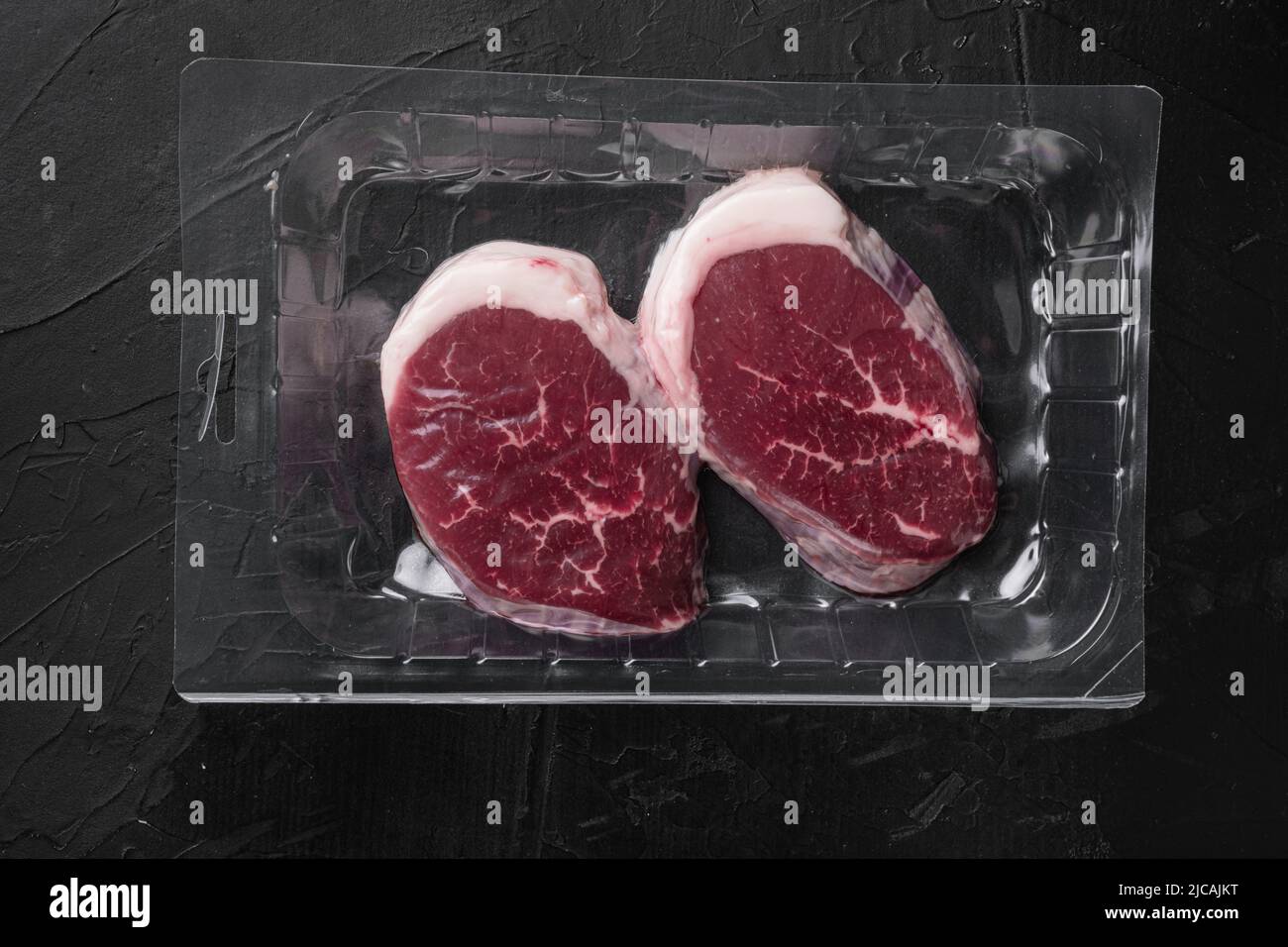 Beef steak vacuum Packed, on black dark stone table background, top ...