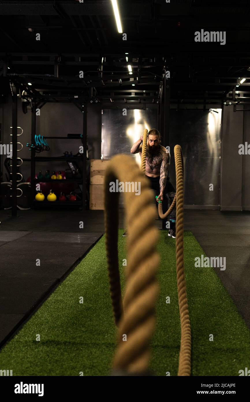 Rope training man warehouse fitness gym muscular exercising exercise ...