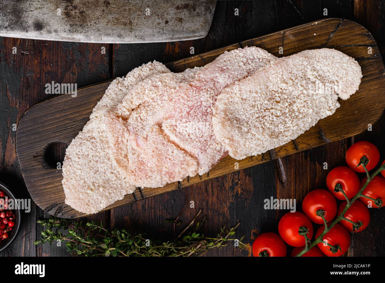 Raw chicken schnitzel in breadcrumbs set, on old dark wooden table ...