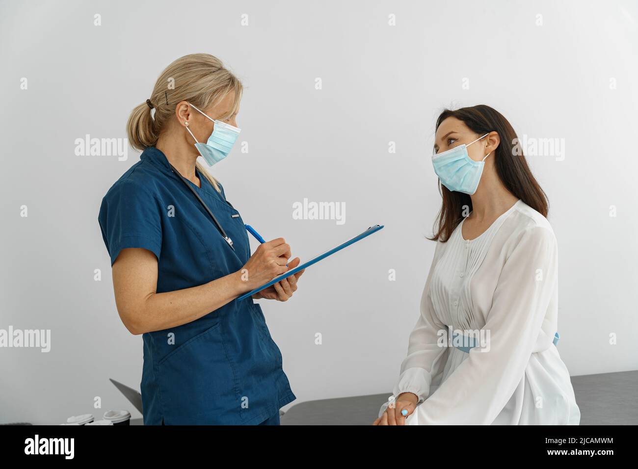 Doctor wearing protection mask against covid taking notes during ...