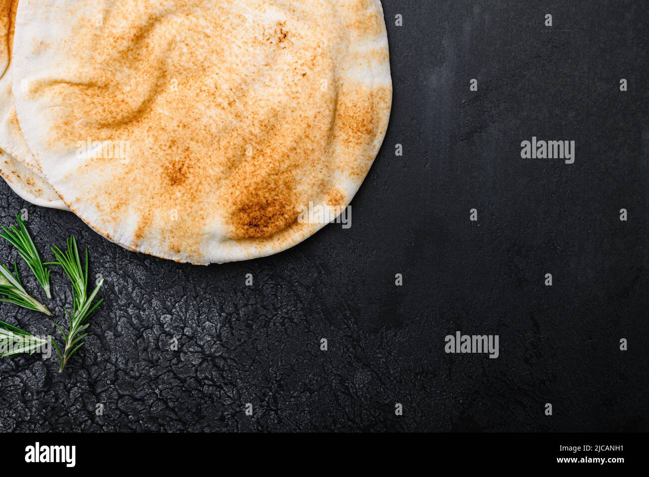 Freshly baked pita bread set, on black dark stone table background, top ...