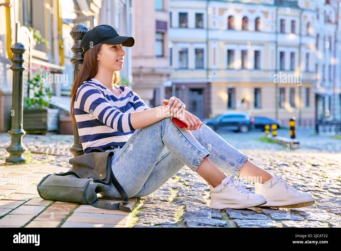 Beautiful teenage female student sitting on the sidewalk Stock Photo ...